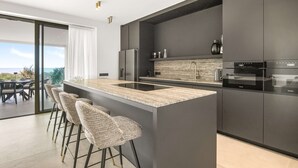 Uma cozinha moderna com uma ilha grande, banquetas e vista para o exterior.
