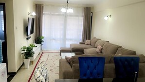 Uma sala de estar moderna com um conjunto de sofás, uma mesa de centro e uma TV fixada na parede.