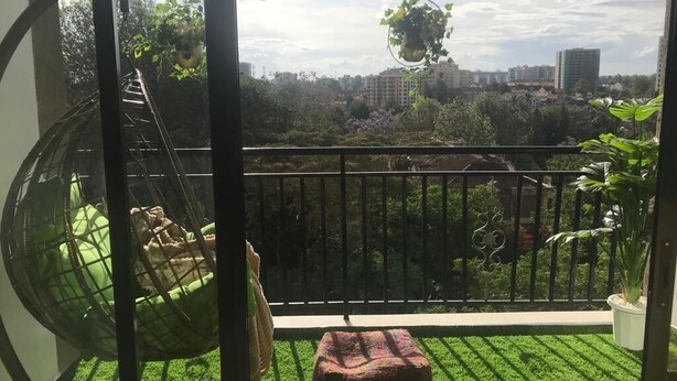 Uma varanda com cadeira suspensa, um banquinho pequeno e plantas em vasos.