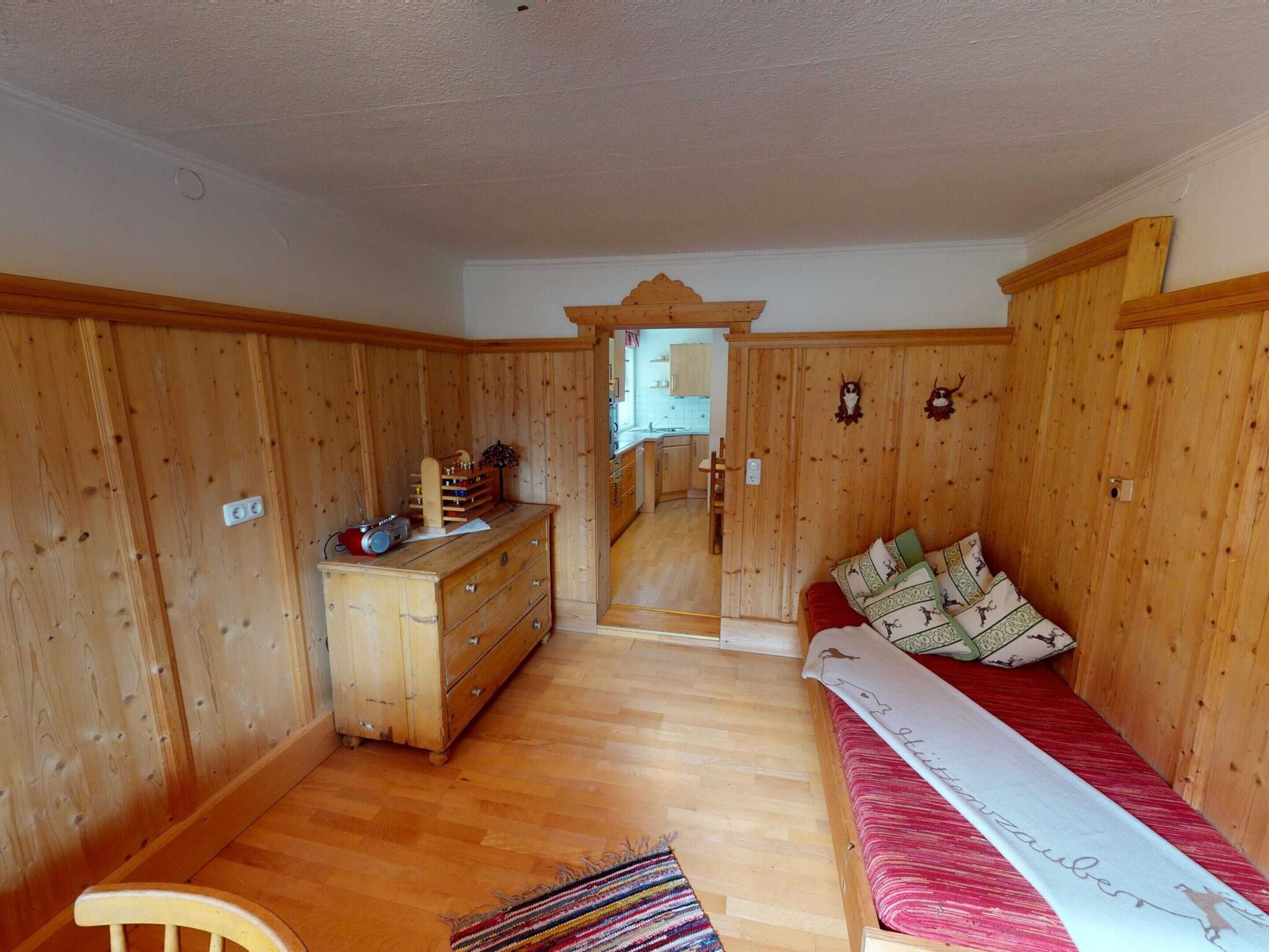Um quarto com painéis de madeira, uma cama, uma cômoda e um espelho.