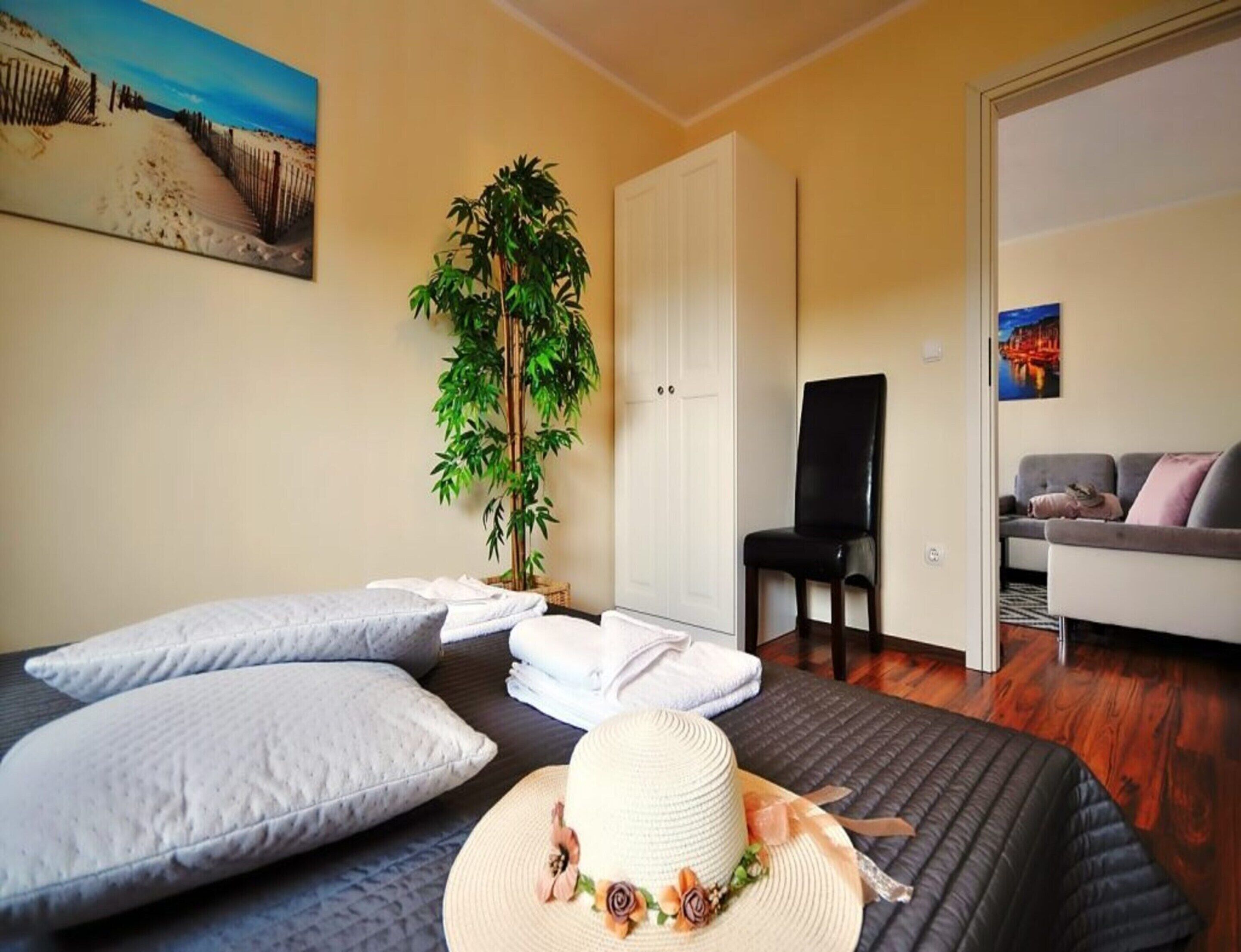 Um quarto com uma cama, uma cadeira, um sofá, uma planta e um quadro na parede.