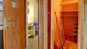 Interior de madeira com uma porta que dá para um banheiro, um esfregão e uma vassoura.