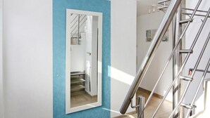 Um interior moderno com uma parede azul de destaque, um espelho e uma escada de metal.