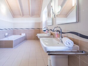 Uma casa de banho moderna com banheira, duas pias e sanita.