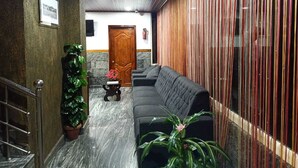 Um corredor com balcão de recepção, porta de madeira, sofá e parede listrada.