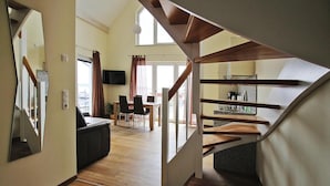 Um interior moderno com escada de madeira, área de refeições e sala de estar.