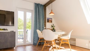 Cozinha moderna com área de jantar, piso de madeira e uma grande janela com cortinas.