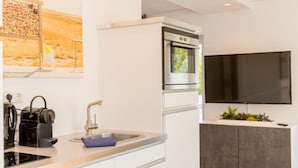Uma cozinha moderna com forno embutido, pia e televisão de tela plana instalada acima do balcão.