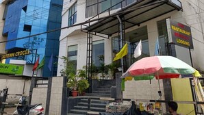 Um edifício com fachada de vidro moderna, entrada coberta e uma placa indicando restaurante e hospedagem.