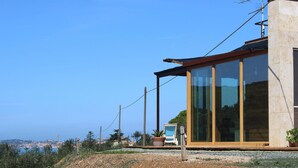 Um edifício moderno com amplas janelas de vidro, fachada de pedra e vista para o mar.