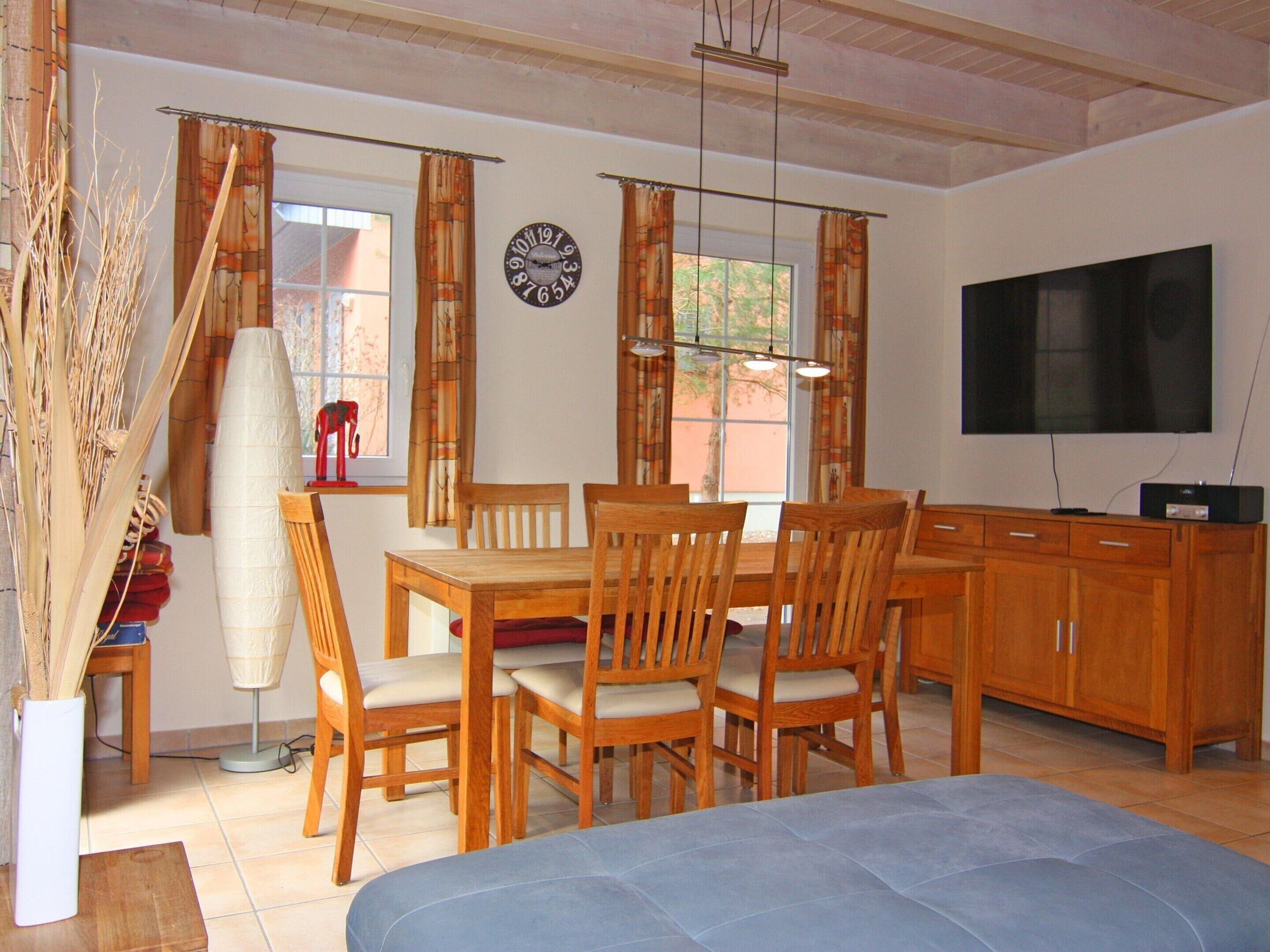 Uma sala de jantar com mobiliário de madeira, uma televisão e um relógio na parede.