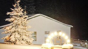 Paisagem coberta de neve com um edifício branco e um arco iluminado grande.
