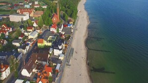Vista aérea de uma cidade costeira com praia, casas e uma igreja.