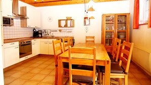 Cozinha com armários de madeira, mesa de jantar, cadeiras, fogão e micro-ondas.
