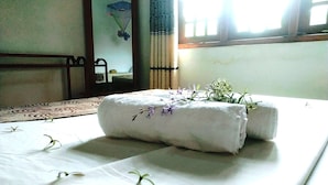 Cama arrumada com toalhas e uma pequena planta em cima.