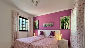 Um quarto com cama, mesas de cabeceira e uma janela com cortinas.