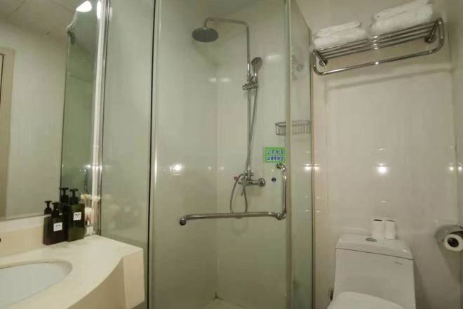 Uma casa de banho moderna com cabine de duche em vidro, sanita e lavatório.