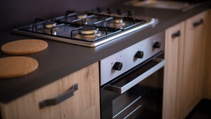 Uma cozinha com fogão a gás, armários de madeira e forno de aço inoxidável.