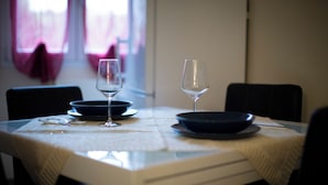 Uma mesa de jantar com dois copos de vinho, uma tigela e um prato, sobre uma toalha de mesa.
