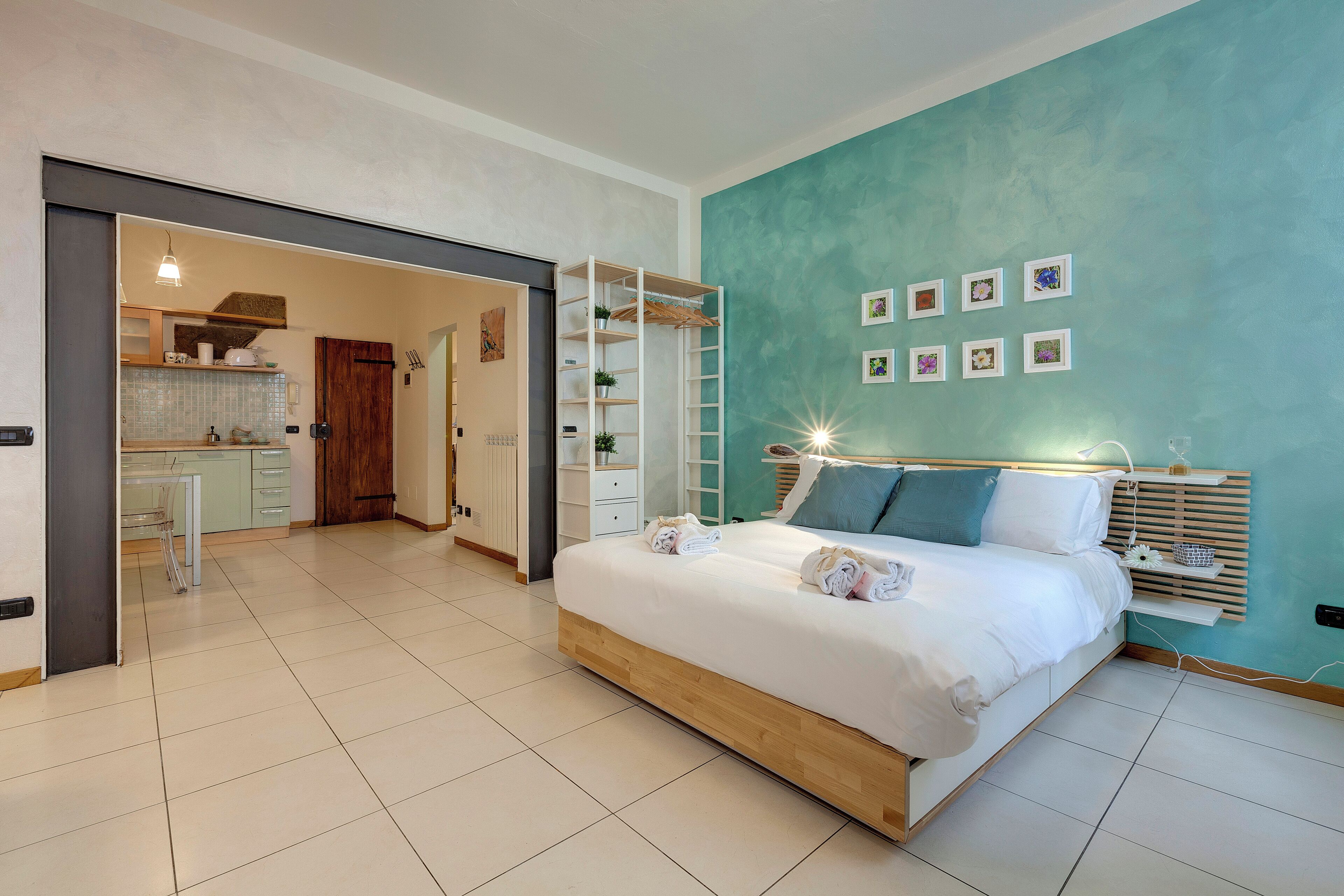 Quarto moderno com cama, guarda-roupa, kitchenette e banheiro.