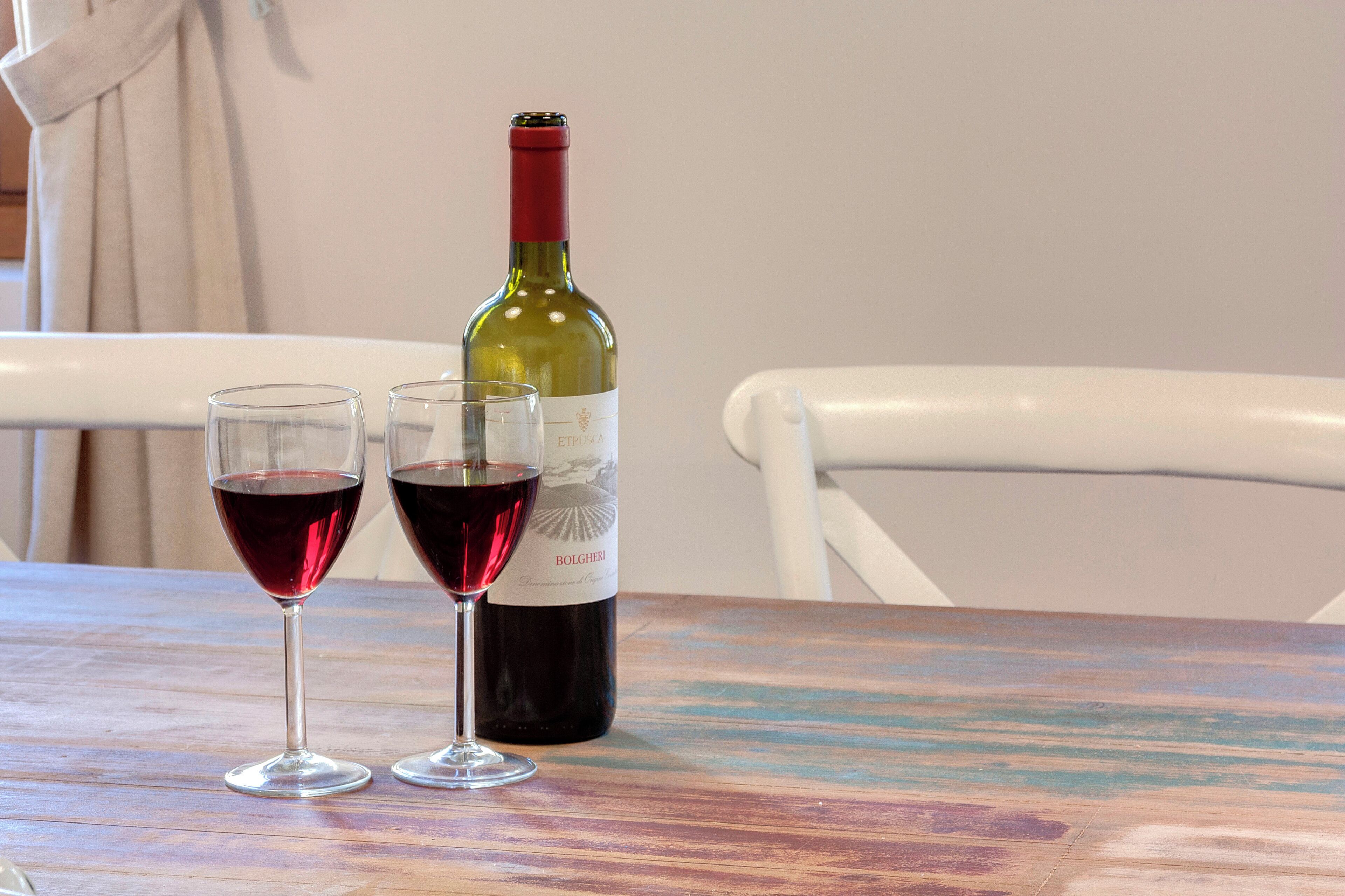 Uma garrafa de vinho e duas taças sobre uma mesa de madeira.