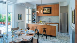 Uma cozinha moderna com uma ilha central, banquetas e uma geladeira.