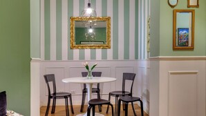 Uma área de refeições com uma mesa redonda e quatro cadeiras, um lustre pendurado e um espelho na parede.