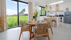 Cozinha moderna com área de jantar, janelas amplas e vista para um campo verde.