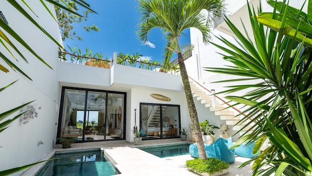 Uma casa moderna com piscina, escadaria e plantas em vasos.