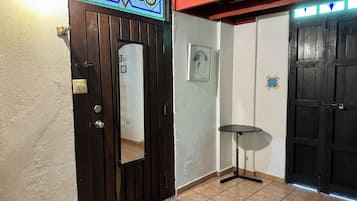 Um corredor com uma porta de madeira, uma mesa redonda pequena e chão de azulejos.