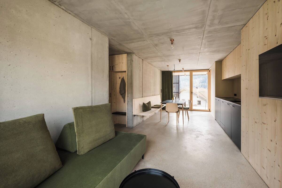 Um interior moderno com um sofá verde, uma mesa de jantar e uma área de cozinha.