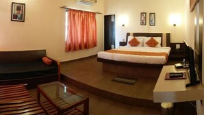Quarto de hotel com cama, sofá, escrivaninha e cadeira.