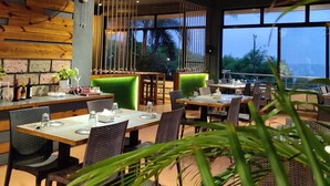 Um restaurante com mesas internas, um bar e vista para o exterior.