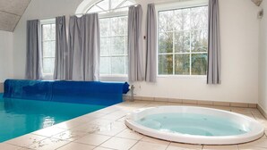 Piscina com deck azul e ofurô, janelas amplas com cortinas e teto inclinado.