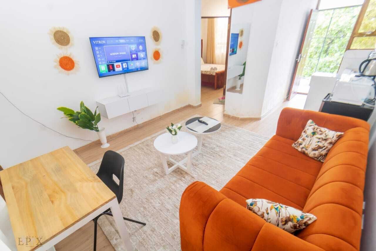 Uma sala de estar moderna com um sofá, uma mesinha e uma TV fixada na parede.