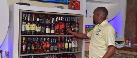 Uma área de bar com prateleiras repletas de diversas garrafas de bebidas alcoólicas.