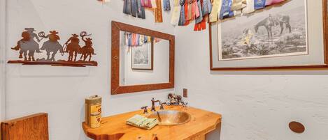 Casa de banho com toucador de madeira, espelho e lavatório.