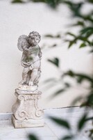 Estátua de pedra de uma figura alada, em um pedestal.