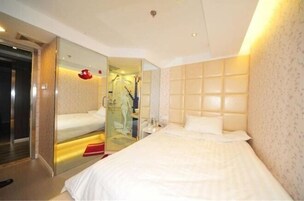 Quarto de hotel com cama, espelho, armário e área de duche.