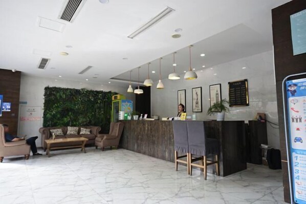 Uma área de recepção moderna com balcão, assentos e uma parede verde.