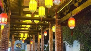 Um edifício tradicional com pilares de tijolo e lanternas penduradas.