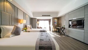 Quarto de hotel com cama grande, mesa de escritório, televisão e cozinha compacta.
