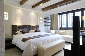 Quarto moderno com uma cama grande, um sofá, uma TV e uma parede de tijolos.