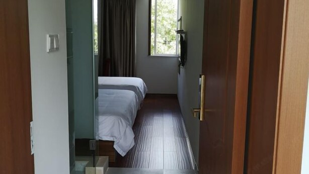 Quarto de hotel com cama, janela, porta e interruptor de luz.