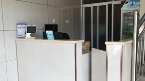 Balcão de recepção com um computador, um código QR e uma placa.