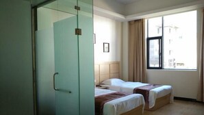 Quarto de hotel com duas camas, divisória de vidro, janela com cortinas e um quadro na parede.