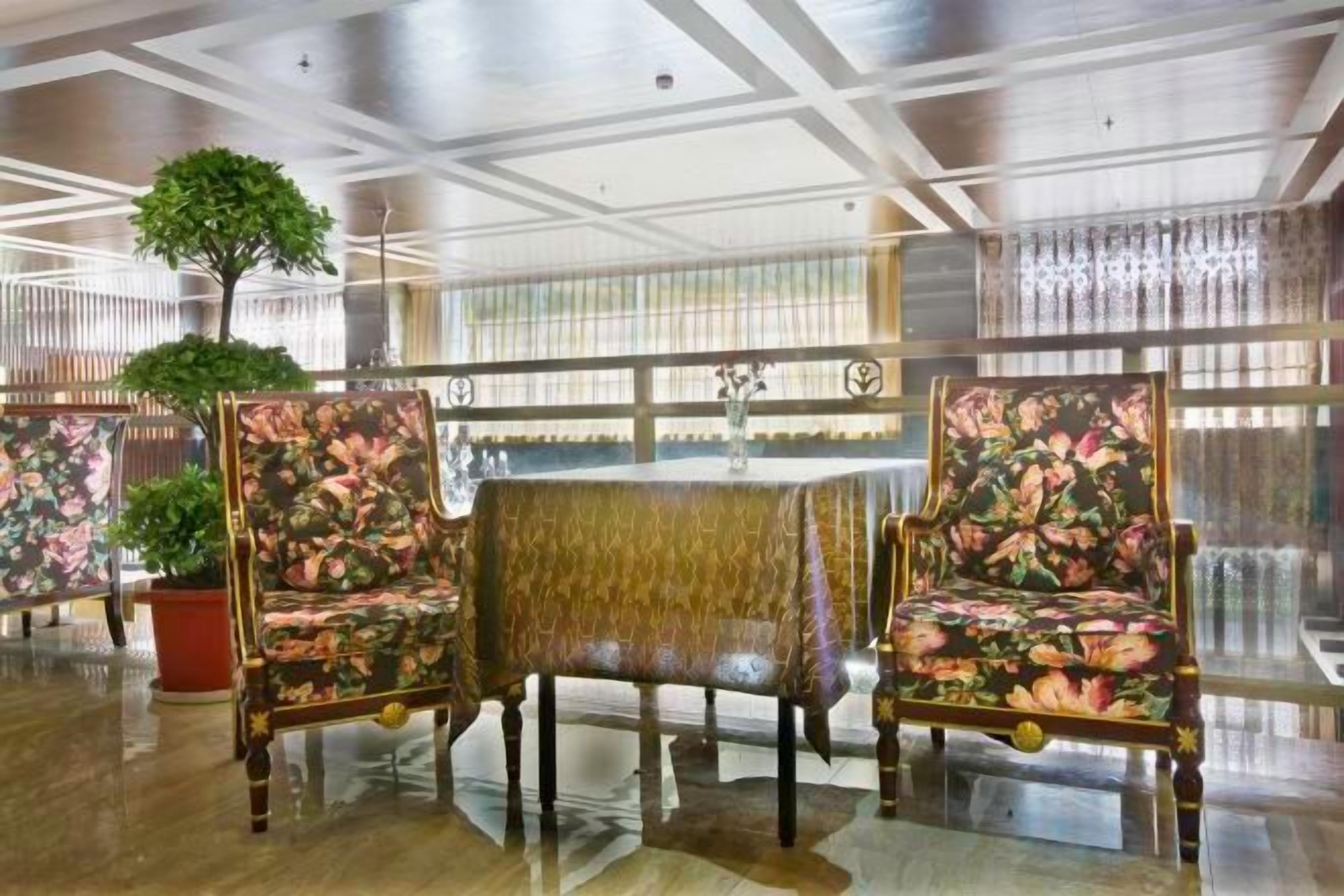 Uma sala de jantar com mesa e cadeiras, um vaso de planta e vista pela janela.