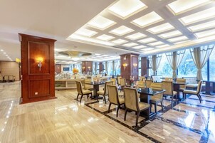 Um hall de hotel espaçoso, com piso de mármore, diversas áreas de estar e amplas janelas.