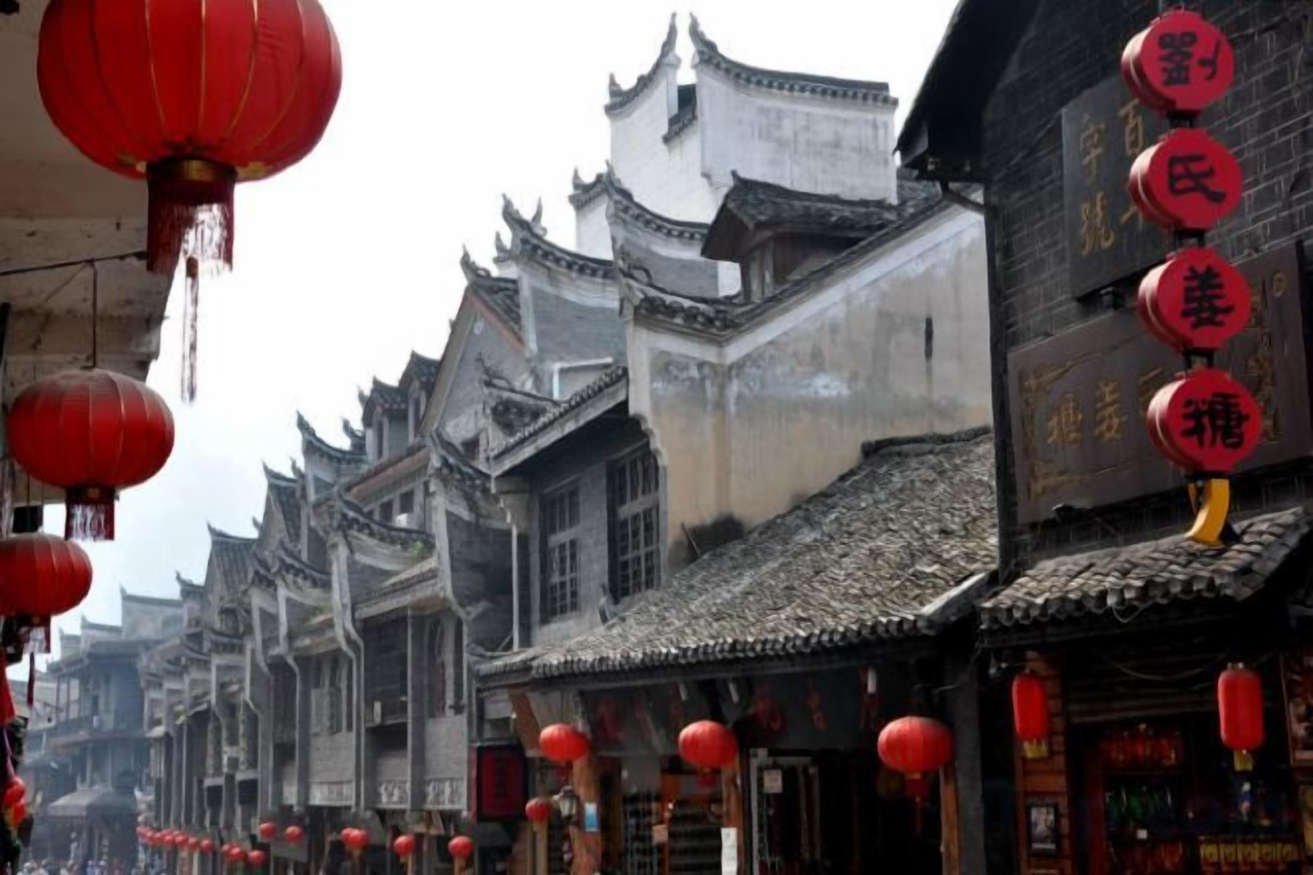 Uma rua tradicional com edifícios antigos, lanternas vermelhas e placas com caracteres chineses.