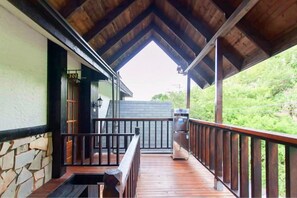 Um espaço ao ar livre coberto com deck de madeira, parede de pedra e vista para o verde.